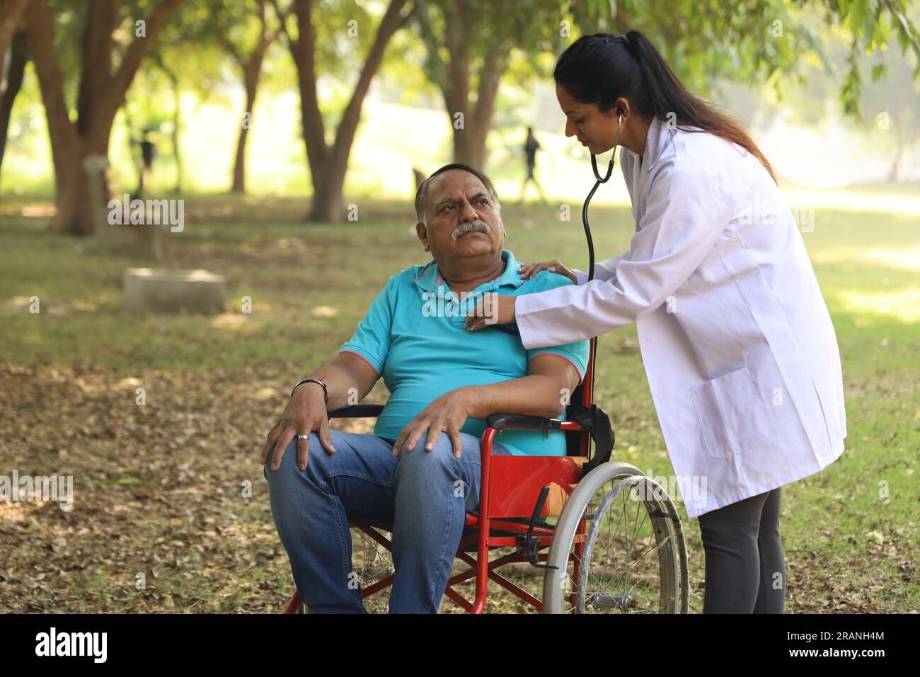 Doctor taking care of senior patient in hospital garden. The patient is ...