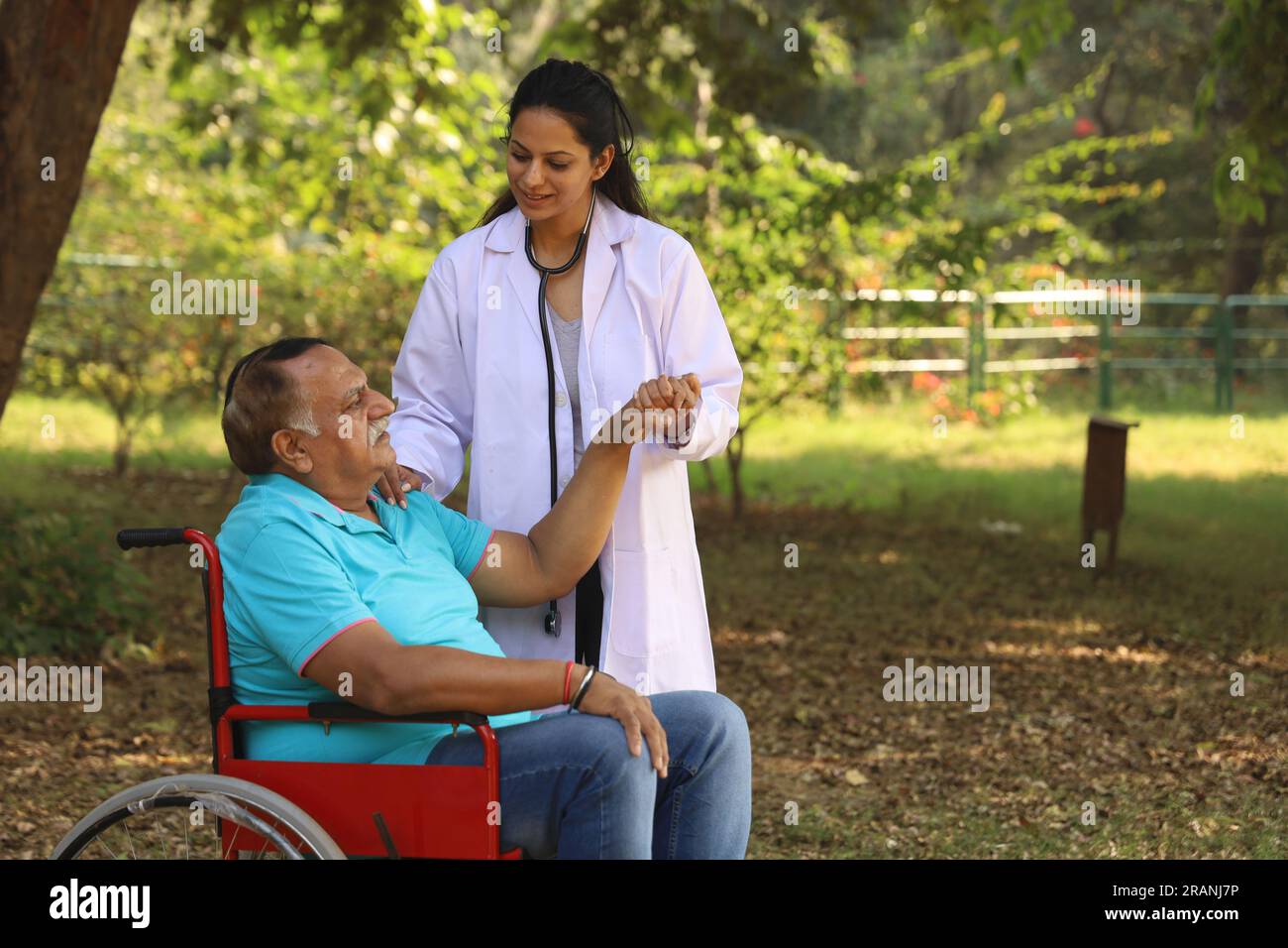 Doctor taking care of senior patient in hospital garden. The patient is ...