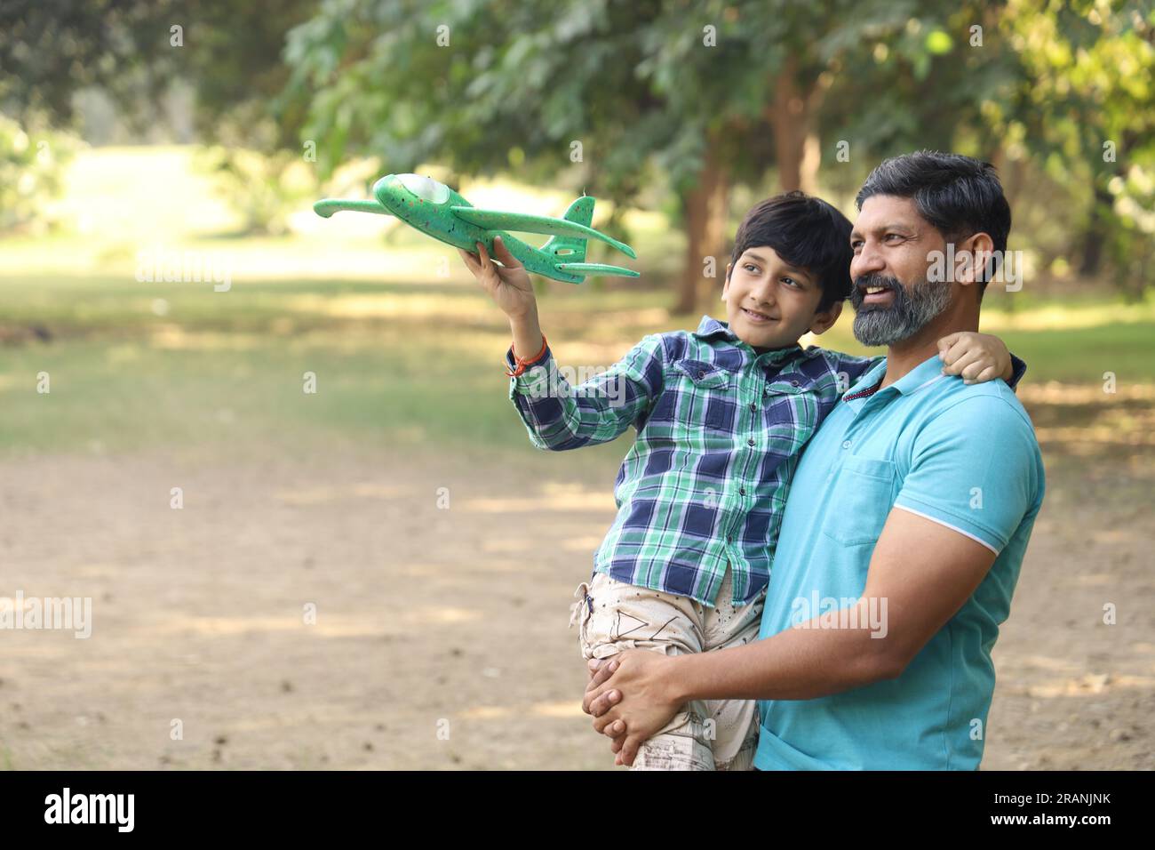 family having a good time in a park. they are grooming their son and ...