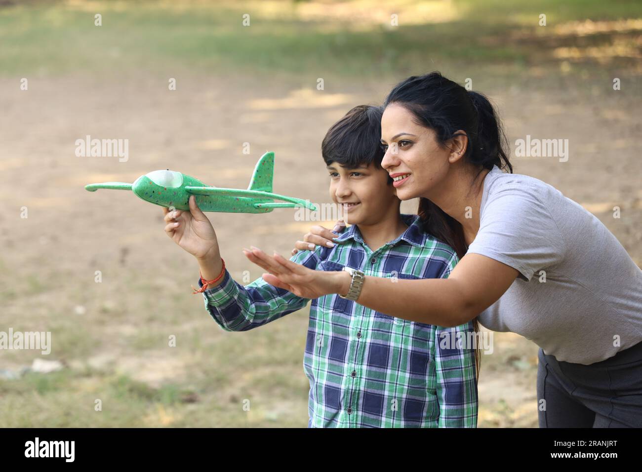 family having a good time in a park. they are grooming their son and ...
