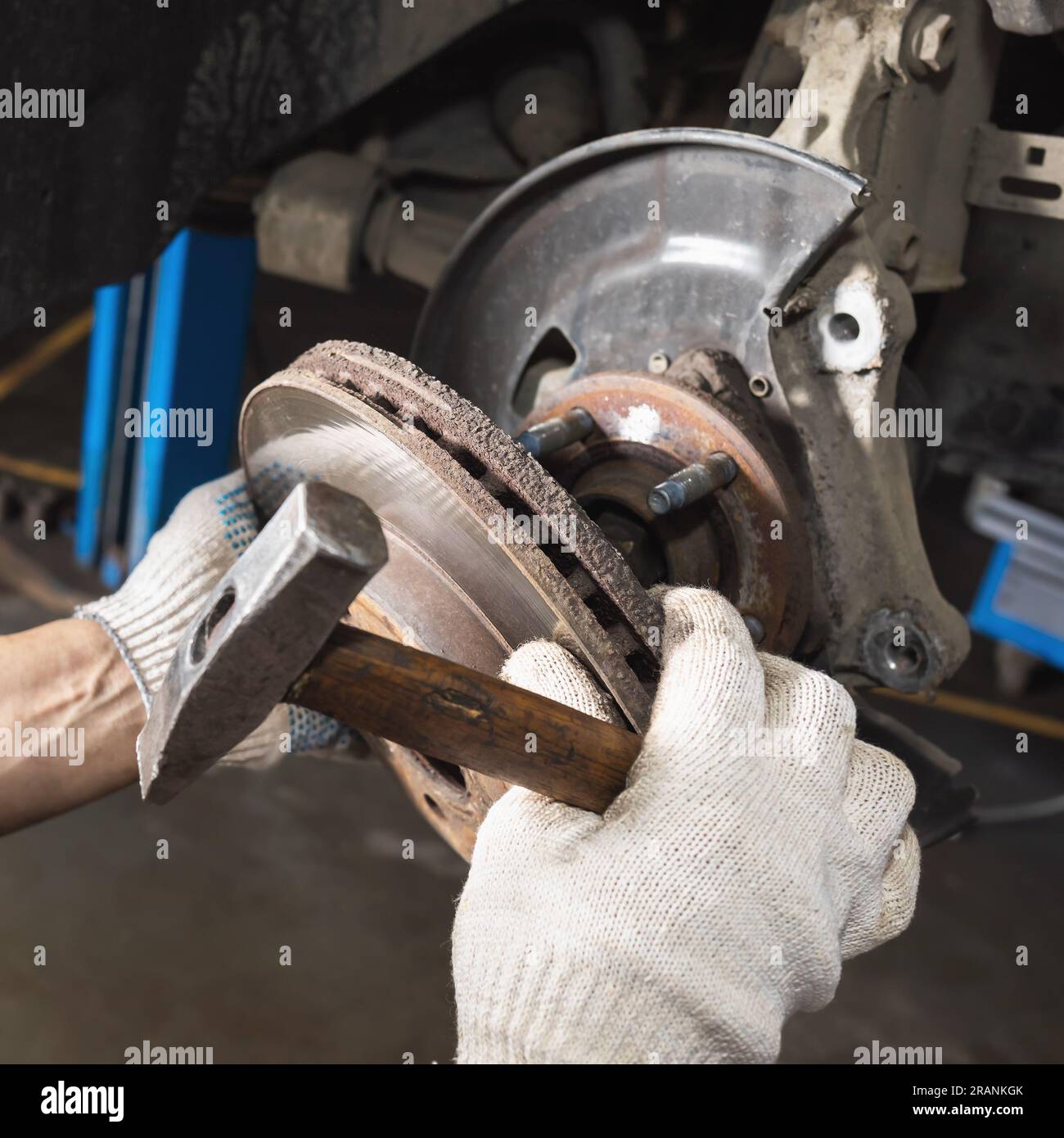 Auto mechanic removes an old rusty brake disc to replace it with a new ...