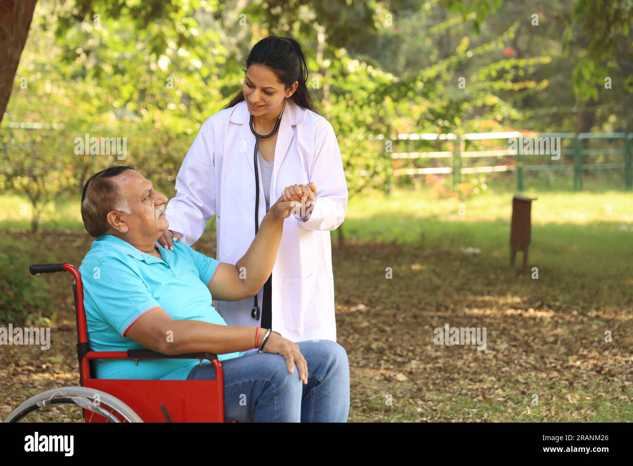 Doctor taking care of senior patient in hospital garden. The patient is ...
