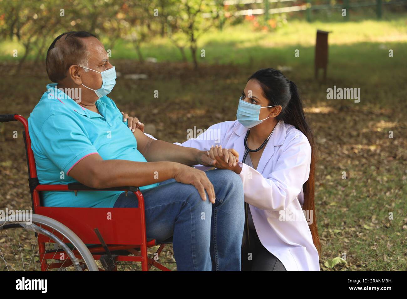Doctor taking care of senior patient in hospital garden. The patient is ...