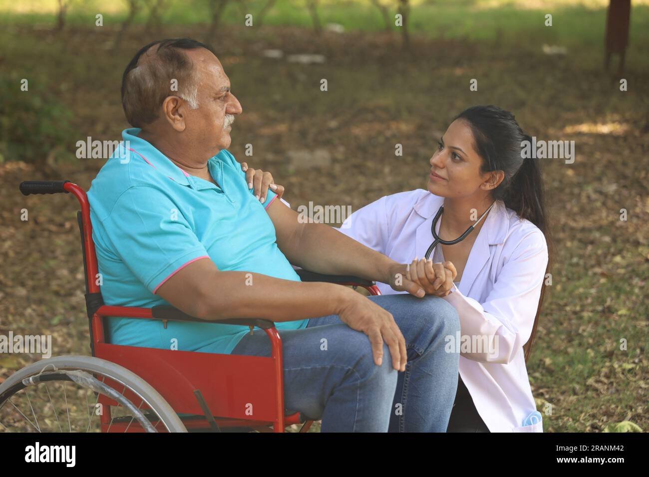Doctor taking care of senior patient in hospital garden. The patient is ...