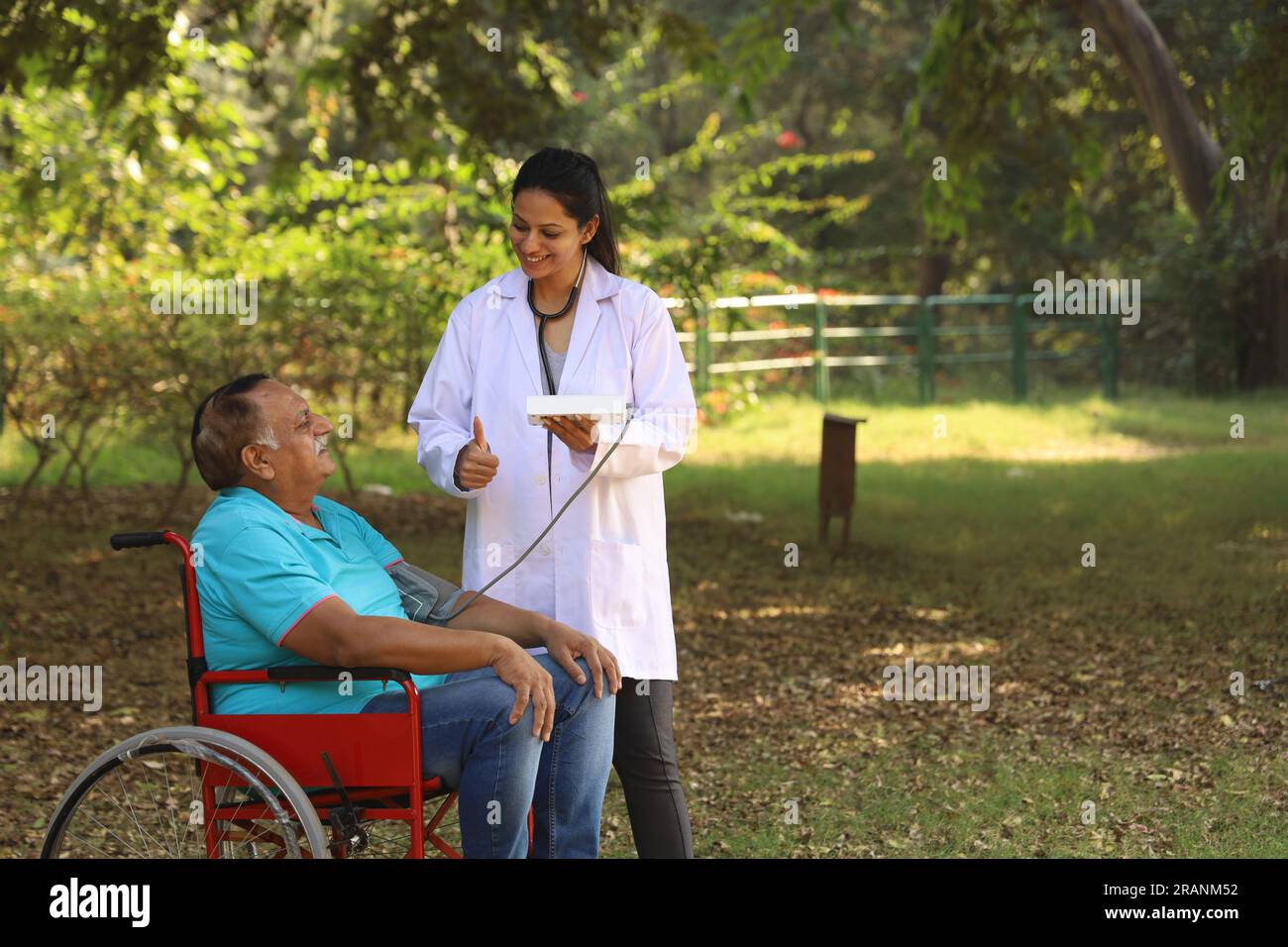 Doctor taking care of old patient in hospital garden. patient is ...