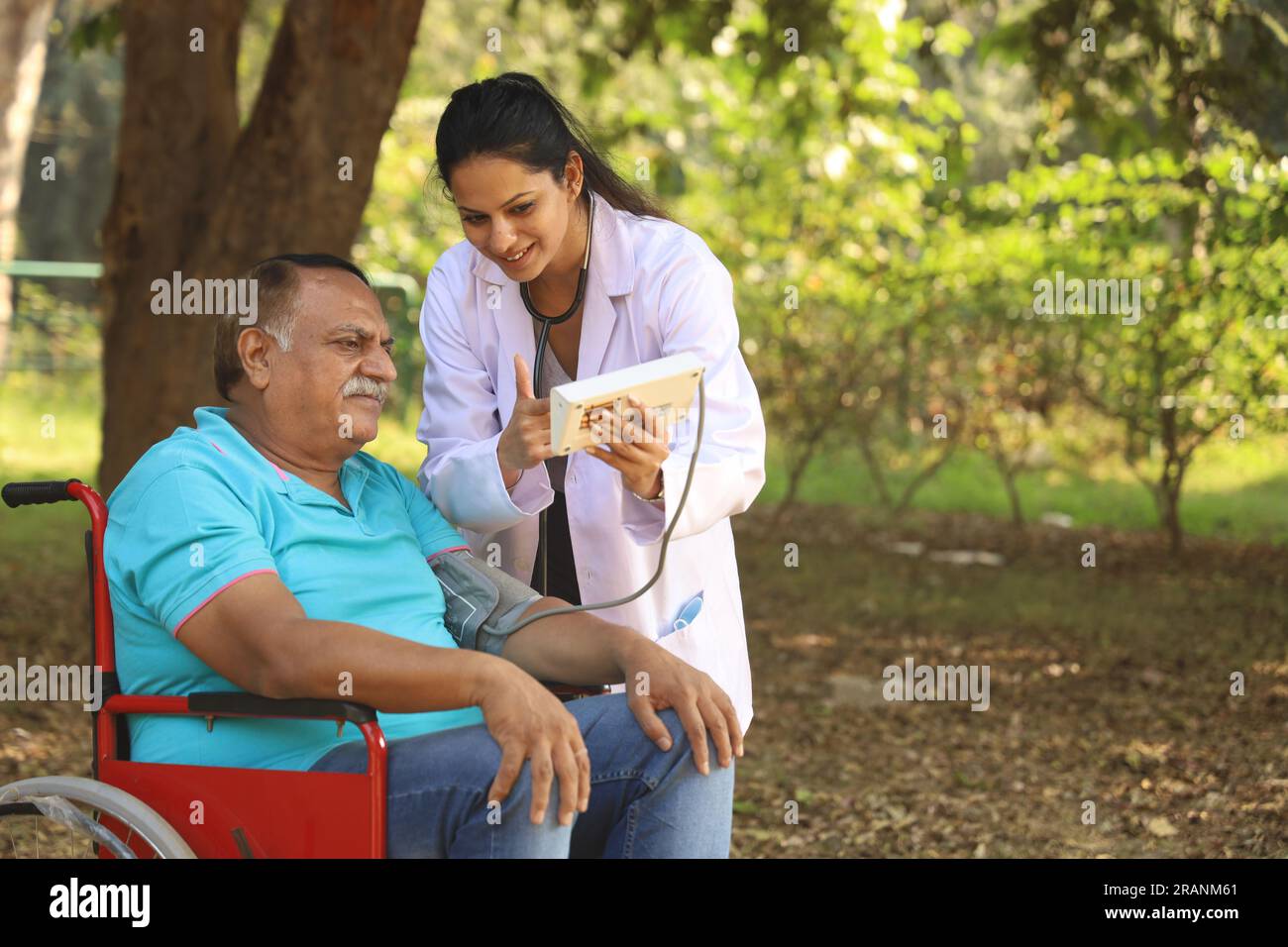 Doctor taking care of old patient in hospital garden. patient is ...
