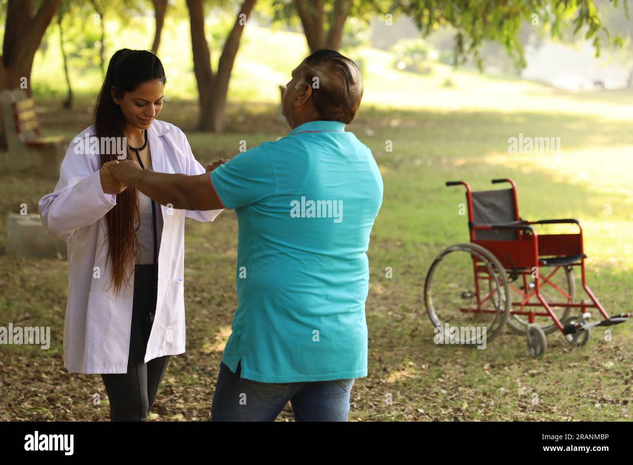 Female Indian Doctor taking care of senior patient in hospital garden ...