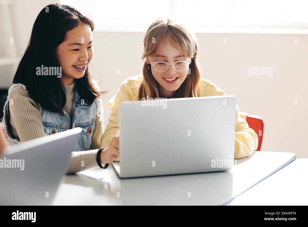 Happy female students assisting each other as they do a digital ...