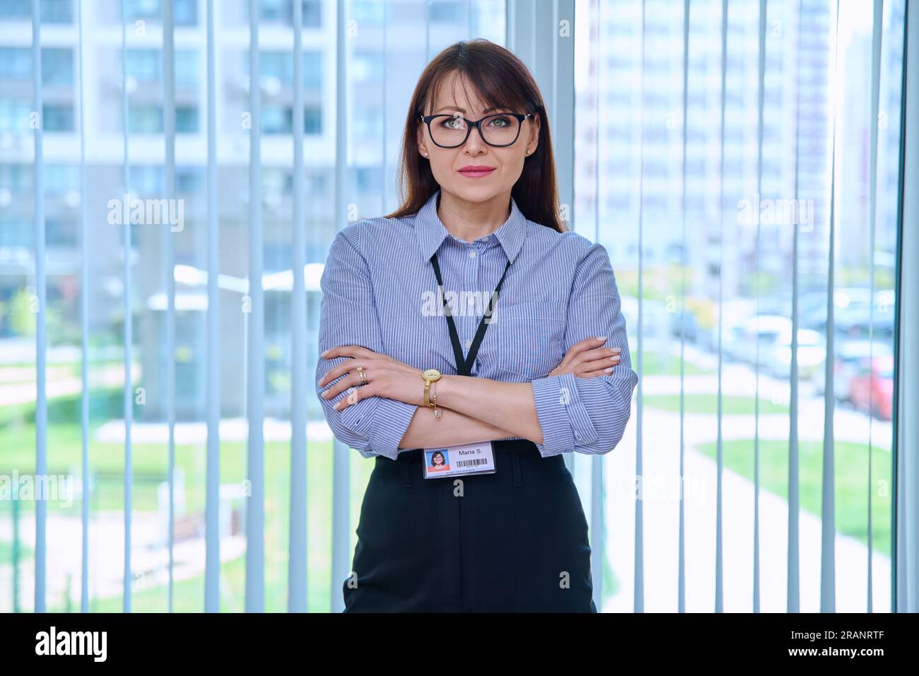Portrait of business woman with badge, id card, in office near window ...