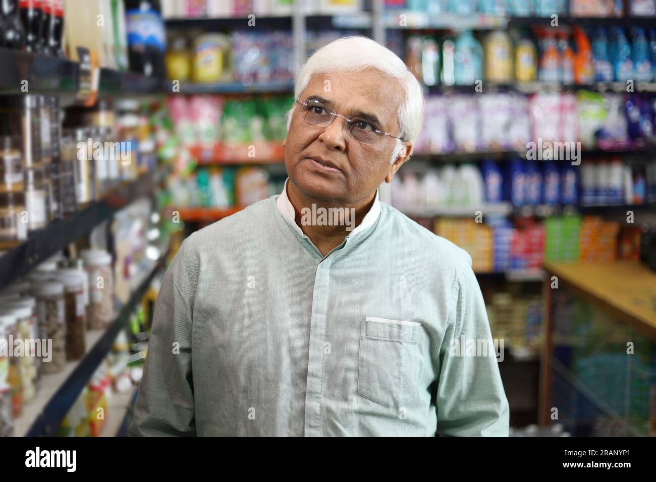 Old man standing in front of product shelf in grocery store. Confused ...
