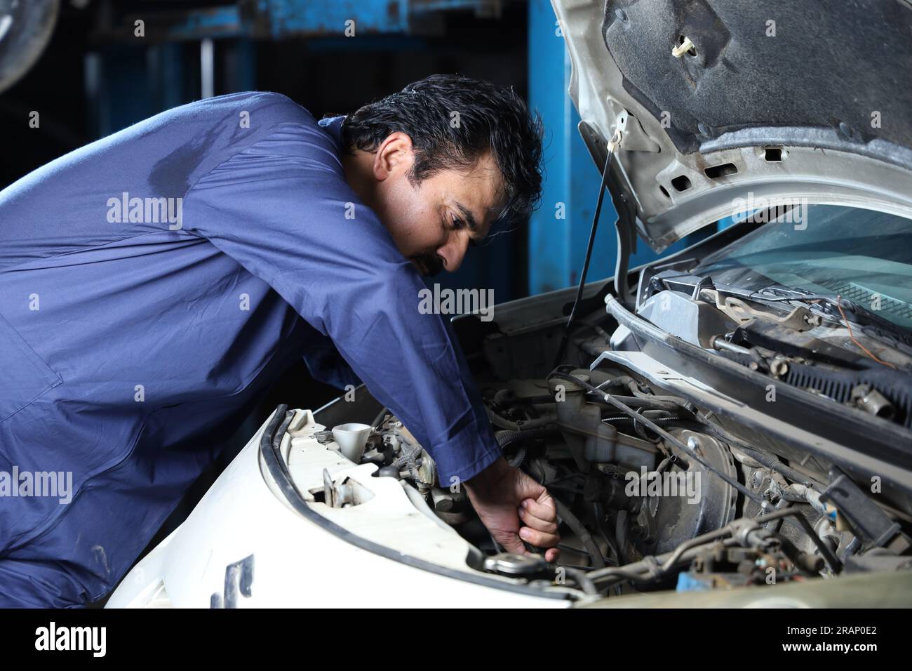 Mechanic in moustache repairing and examining the car. Car specialist ...