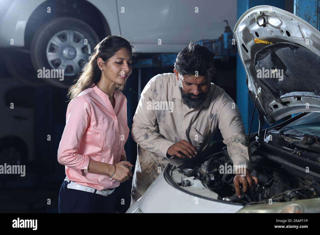 Mechanic in moustache repairing and examining the car. Car specialist ...