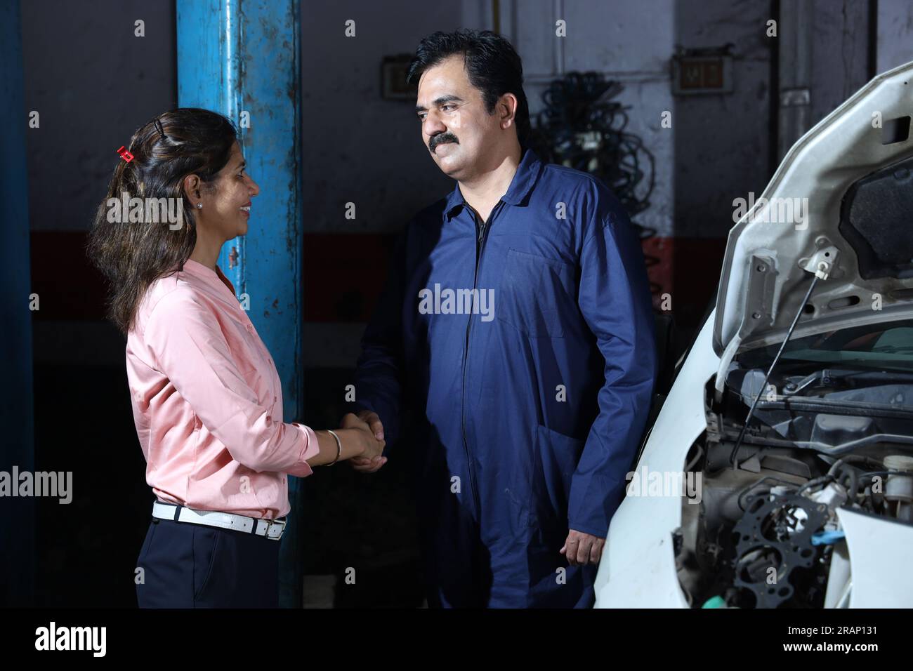 Mechanic standing with happy customer shaking hands. Portraying ...
