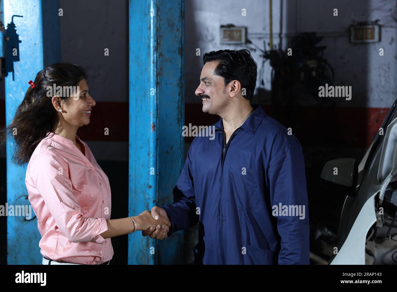 Mechanic standing with happy customer shaking hands. Portraying ...