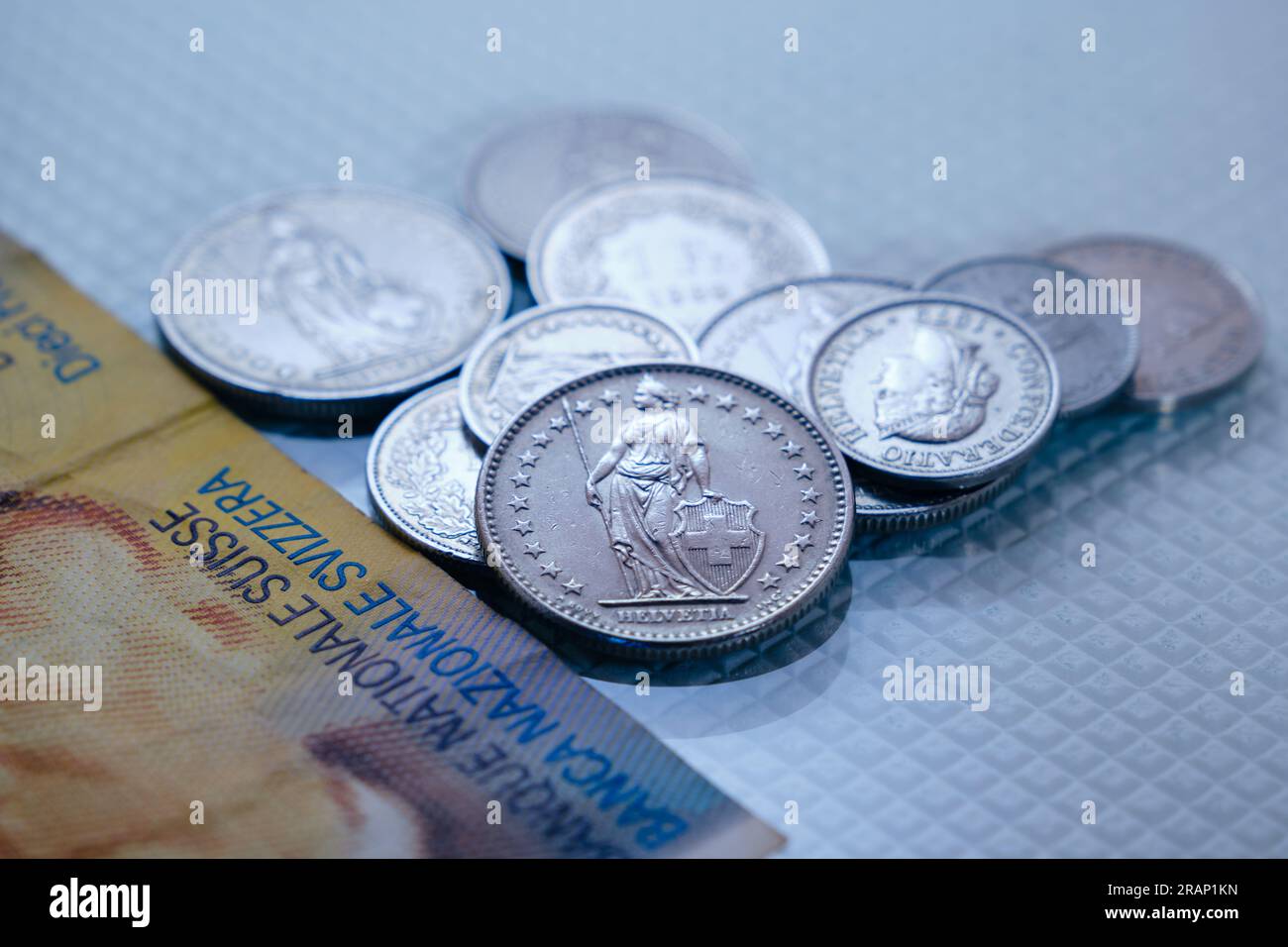 Swiss franc coins resting on a shiny textured base, close up partial ...