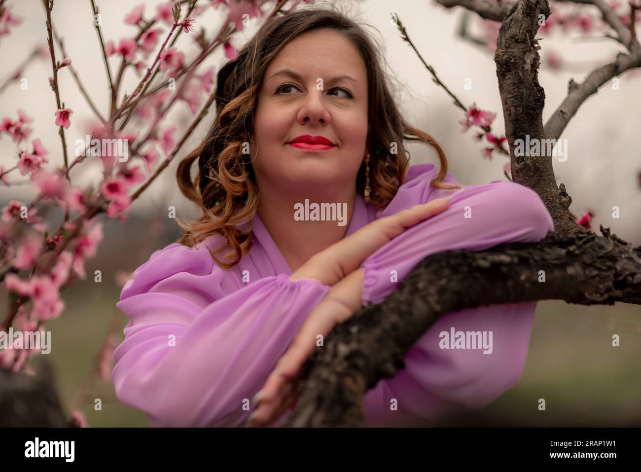 Woman peach blossom. Happy curly woman in pink dress walking in the ...