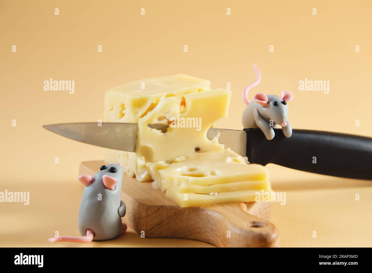 Little plasticine gray mice cut a piece of cheese. Beige background ...