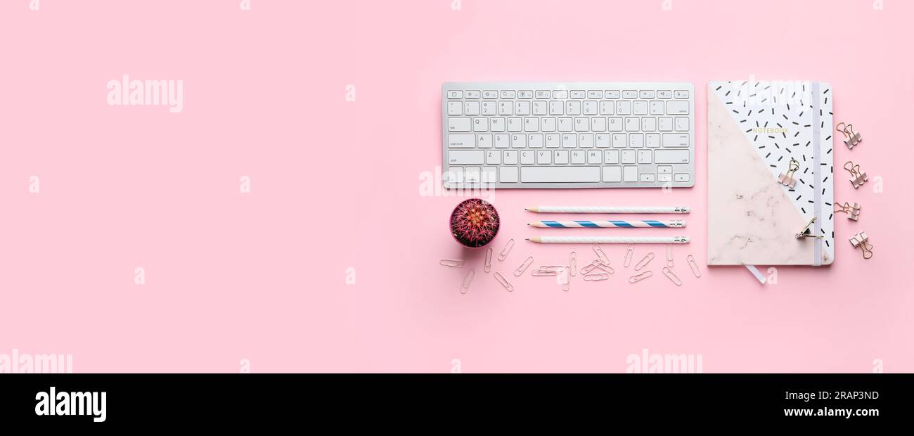 PC keyboard with cactus and stationery on pink background with space ...
