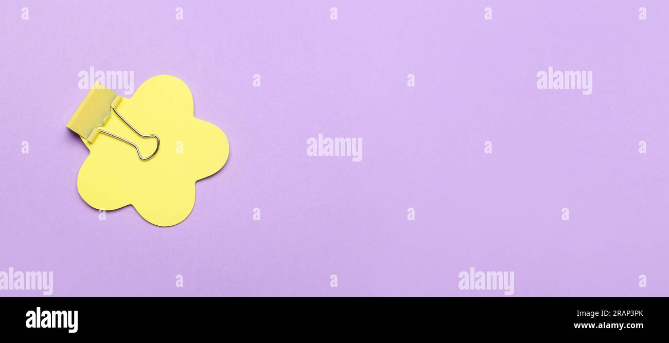 Yellow sticky note with binder clip on lilac background with space for ...