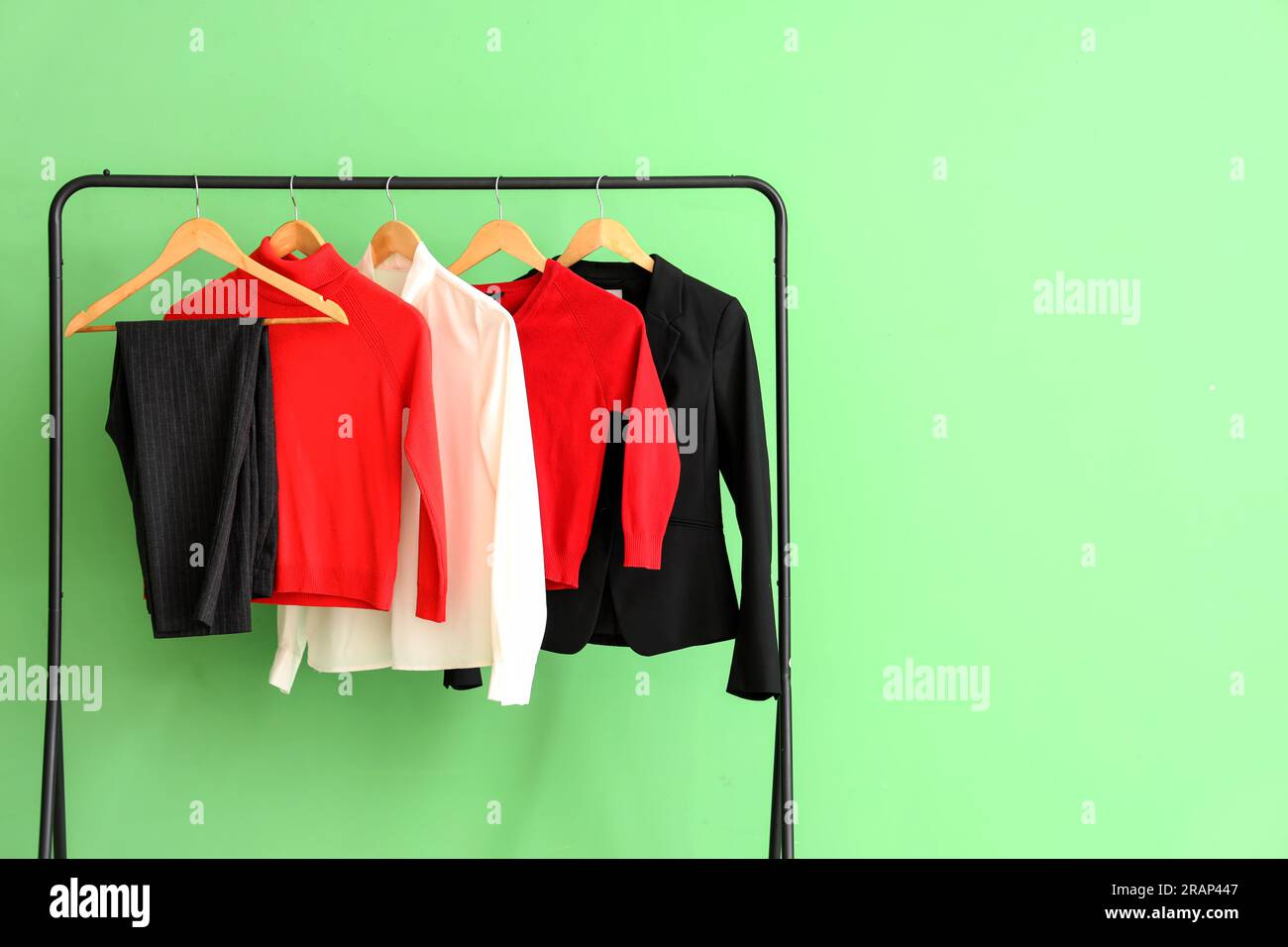 Stylish school uniform hanging on rack near green wall in room Stock ...
