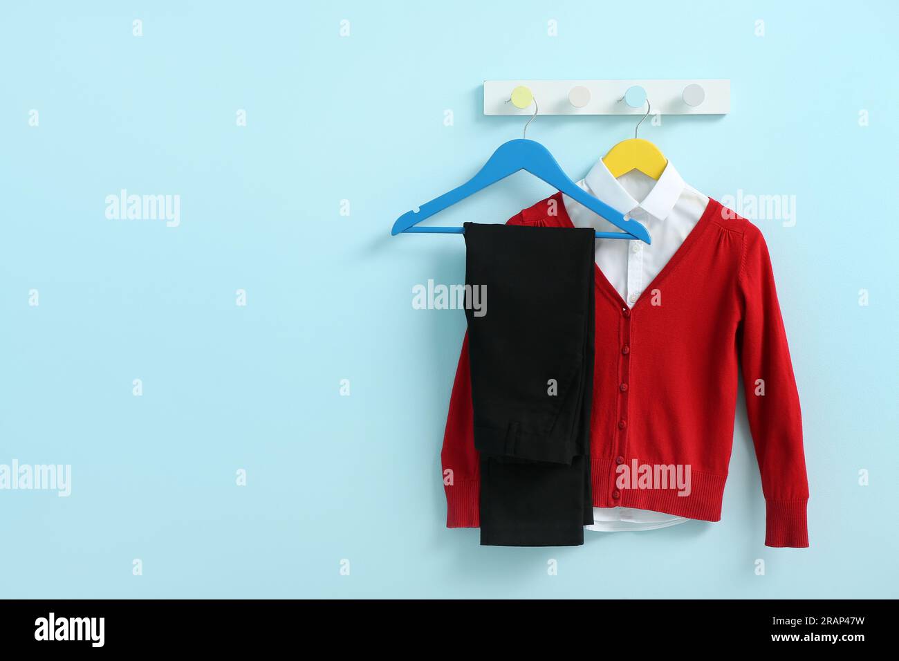 Stylish school uniform hanging on rack against blue wall Stock Photo ...