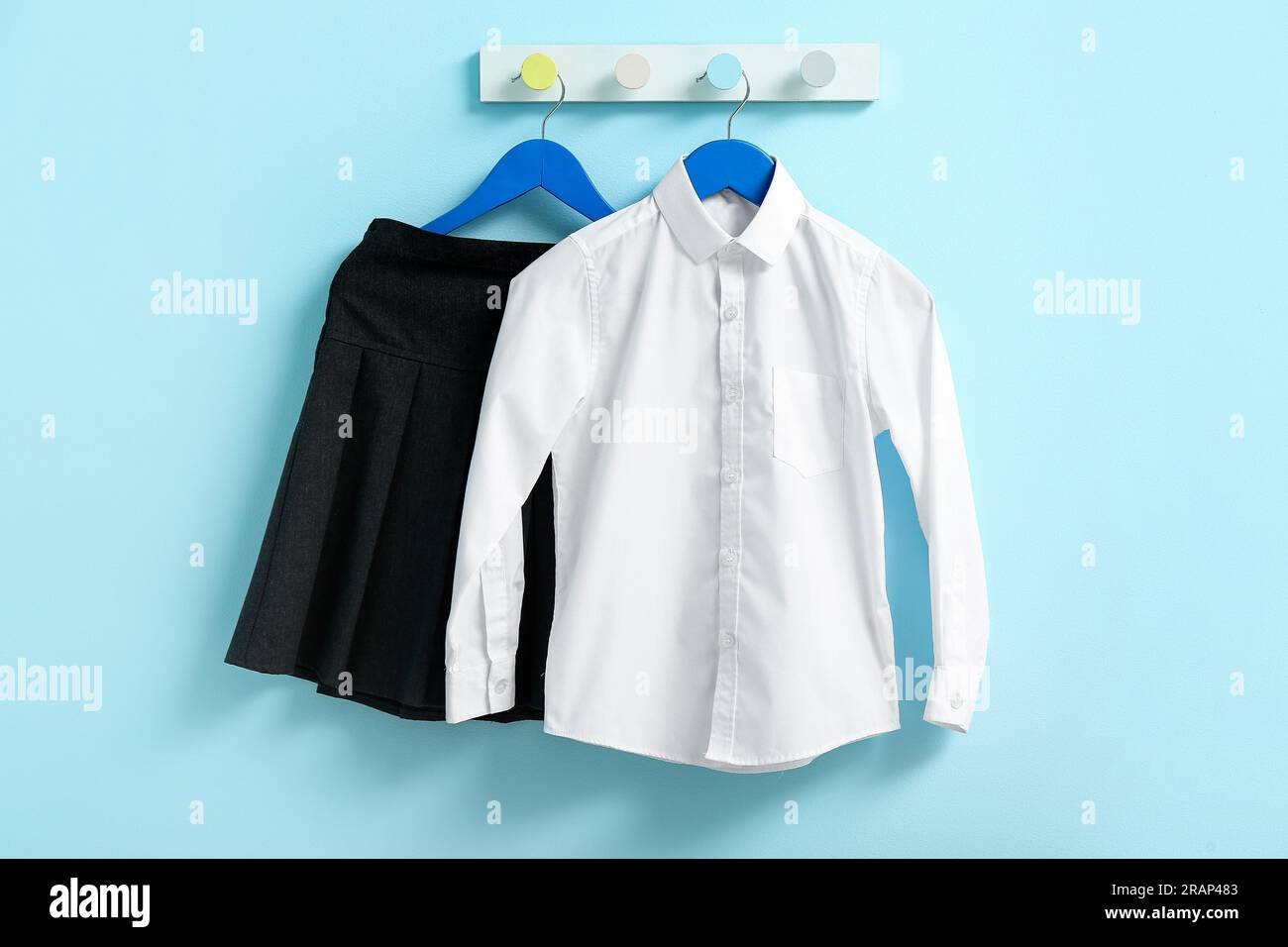 Stylish school uniform hanging on rack against blue wall Stock Photo ...