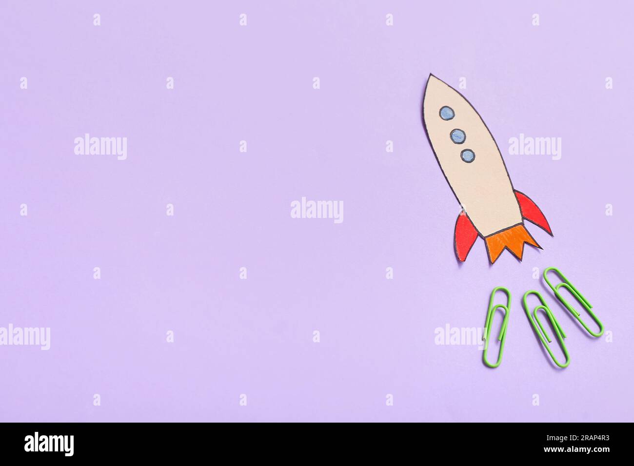Paper rocket with clips on purple background Stock Photo - Alamy