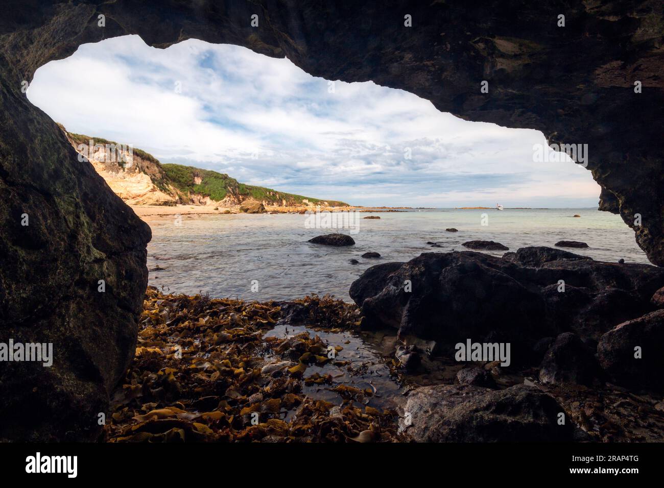 rocks and water with clouds from inside a cave on Broughton Island ...