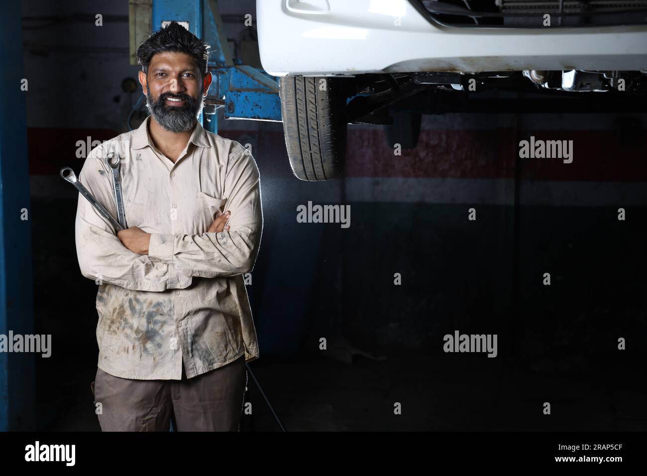 Portrait of a happy car mechanic in moustache standing beside car in ...