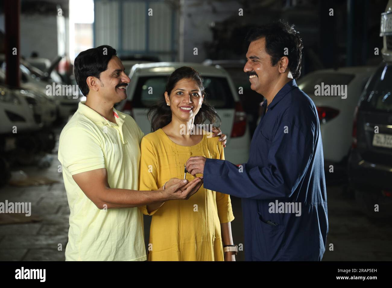 Indian car mechanic delivering the car keys to the happy customers ...