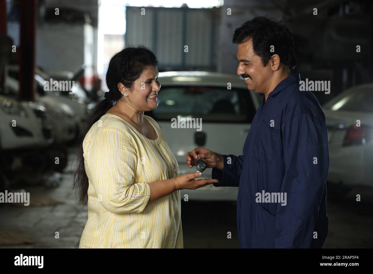 Indian car mechanic delivering the car keys to the happy customers ...