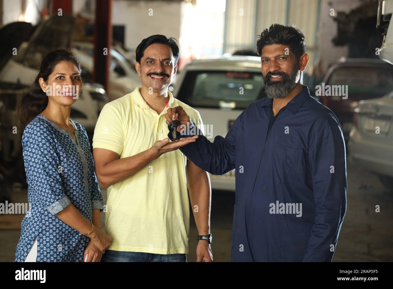 Indian car mechanic delivering the car keys to the happy customers ...