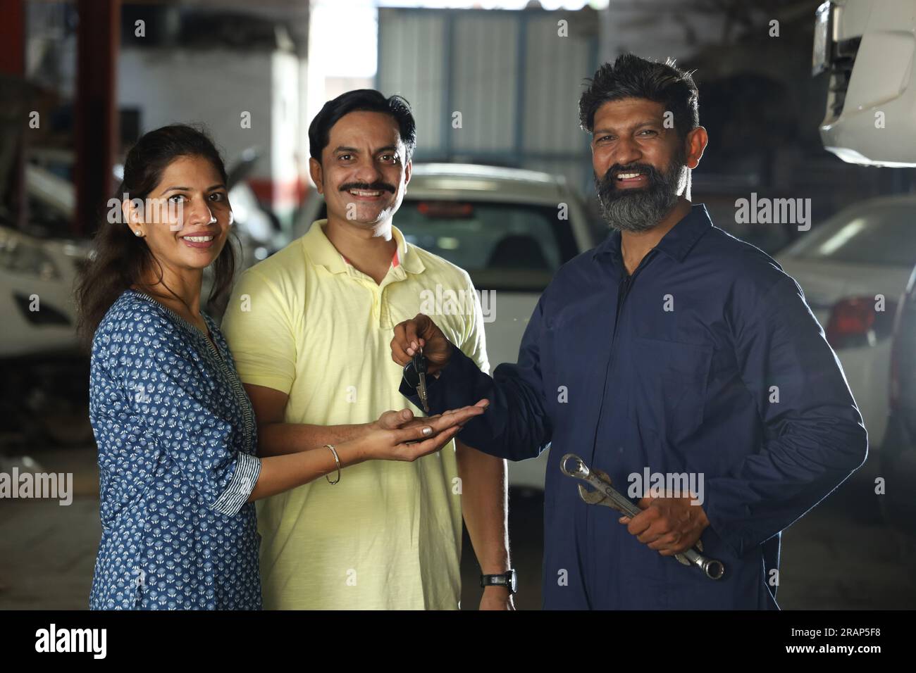 Indian car mechanic delivering the car keys to the happy customers ...