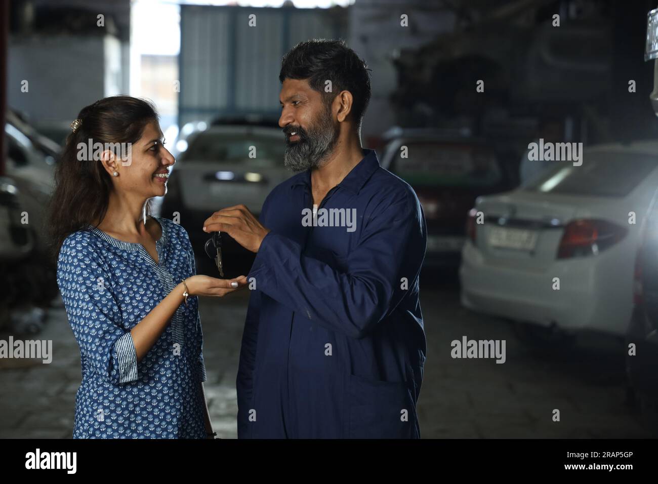 Indian car mechanic delivering the car keys to the happy customers ...