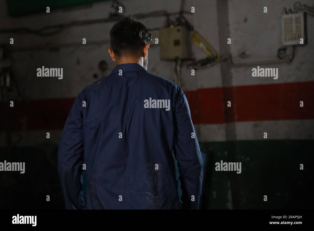 Back of sad car mechanic thinking and standing in a workshop. Hard ...