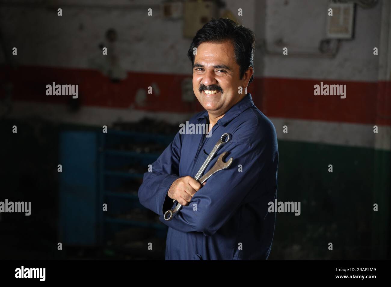 Portrait of a happy car mechanic in moustache standing beside car in ...