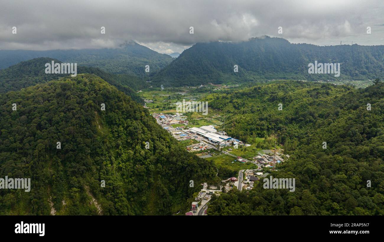 Aerial drone of small town among the mountains with jungle and ...