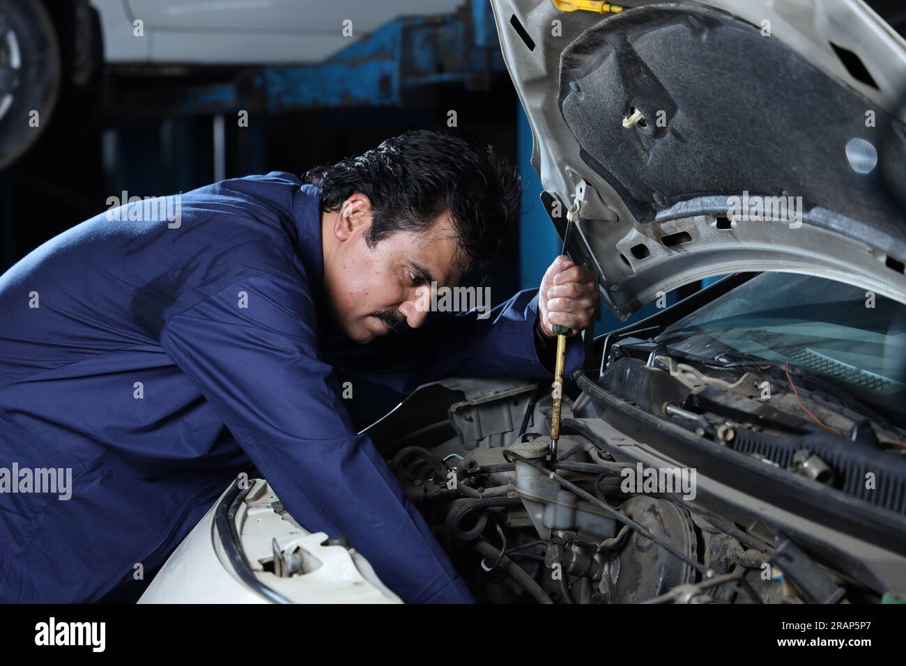 Portrait of a car mechanic in moustache repairing and examining the car ...