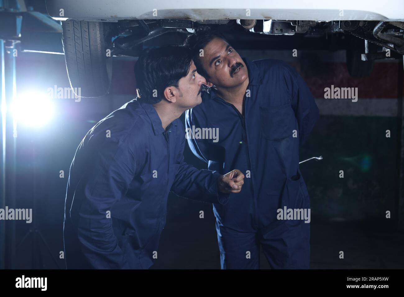 Car specialists examining the lifted car. Professional repairmen ...