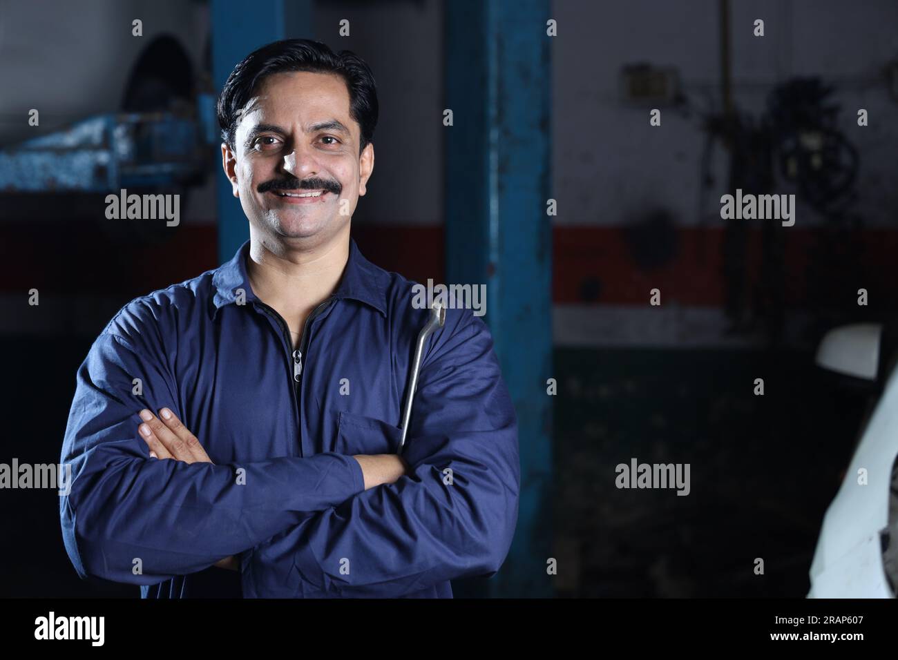 Portrait of a happy car mechanic in moustache standing beside car in ...