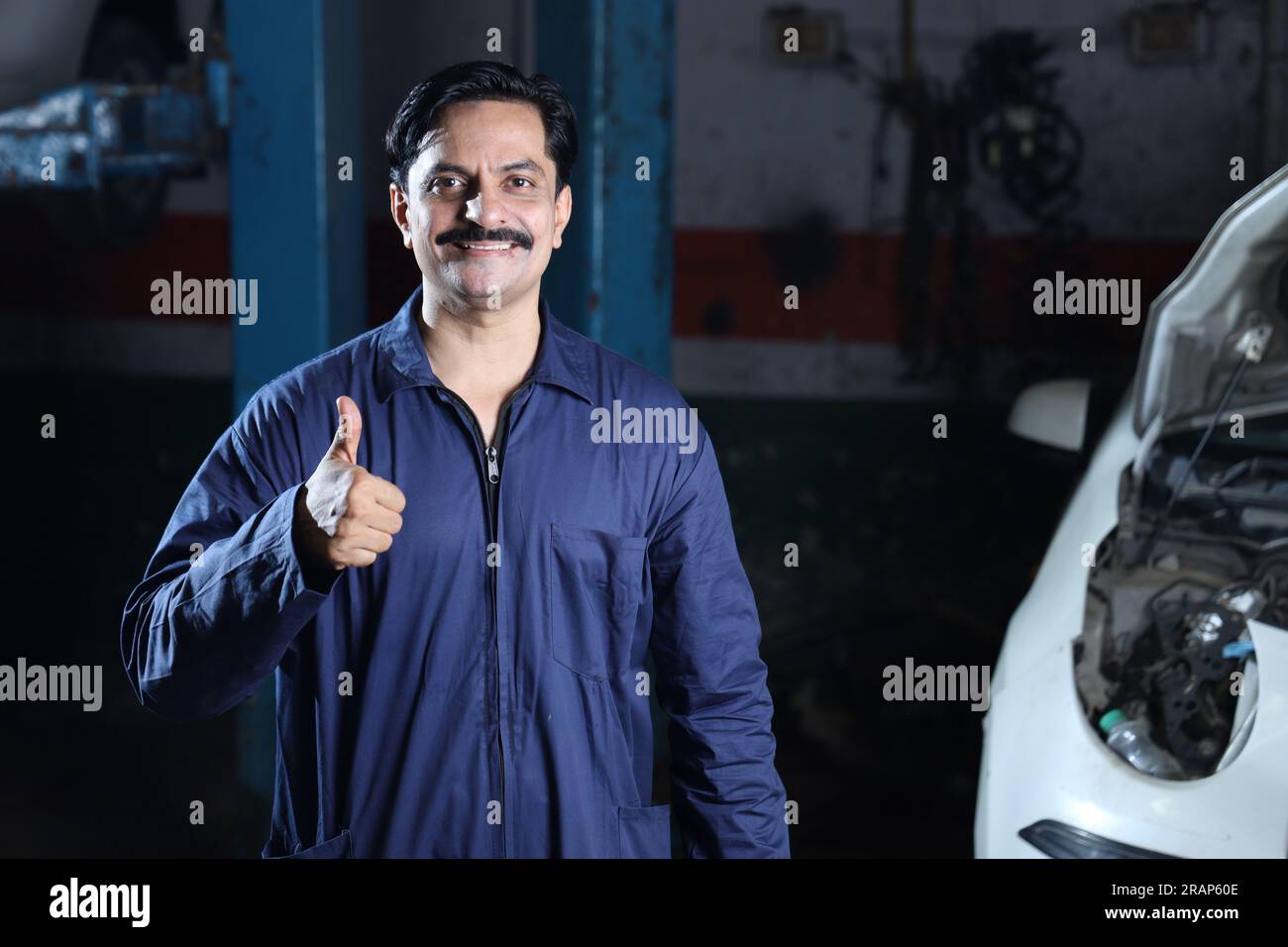 Portrait of a happy car mechanic in moustache standing beside car in ...