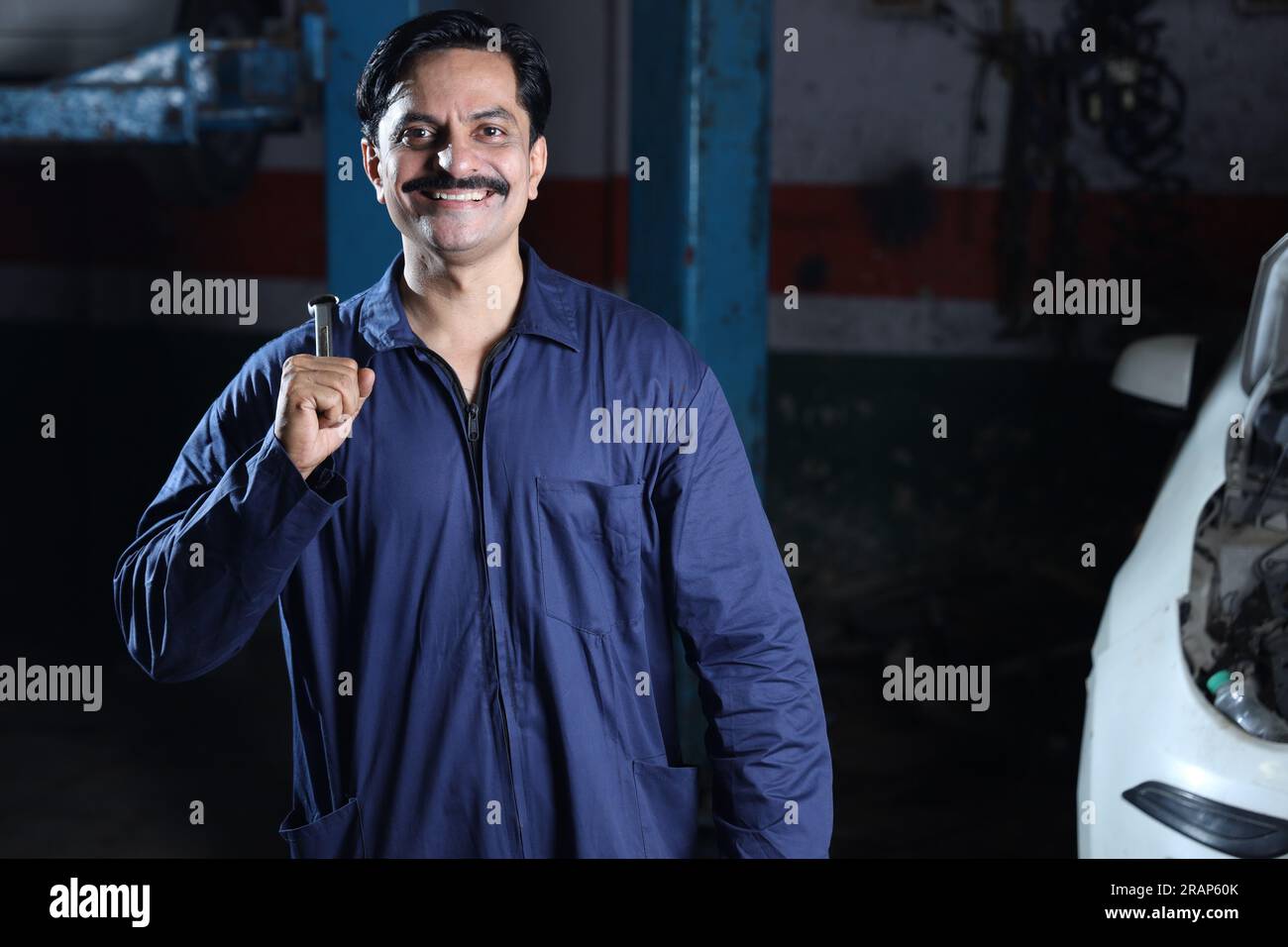 Portrait of a happy car mechanic in moustache standing beside car in ...