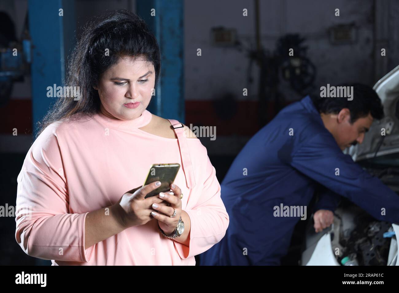 Happy customer at car workshop making online payment using smart phone ...