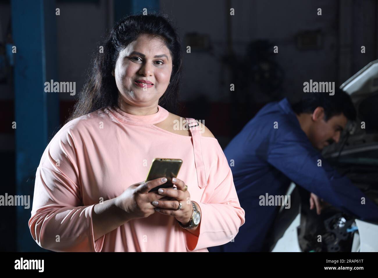 Happy customer at car workshop making online payment using smart phone ...