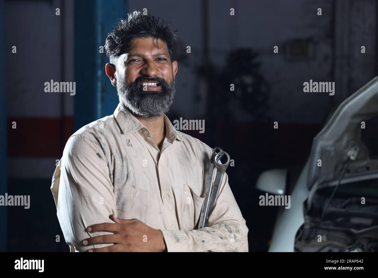 Portrait of a happy car mechanic in moustache standing beside car in ...
