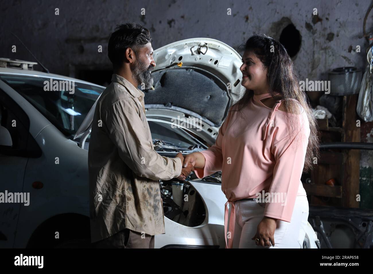 car mechanic standing with the happy customer shaking hands together ...