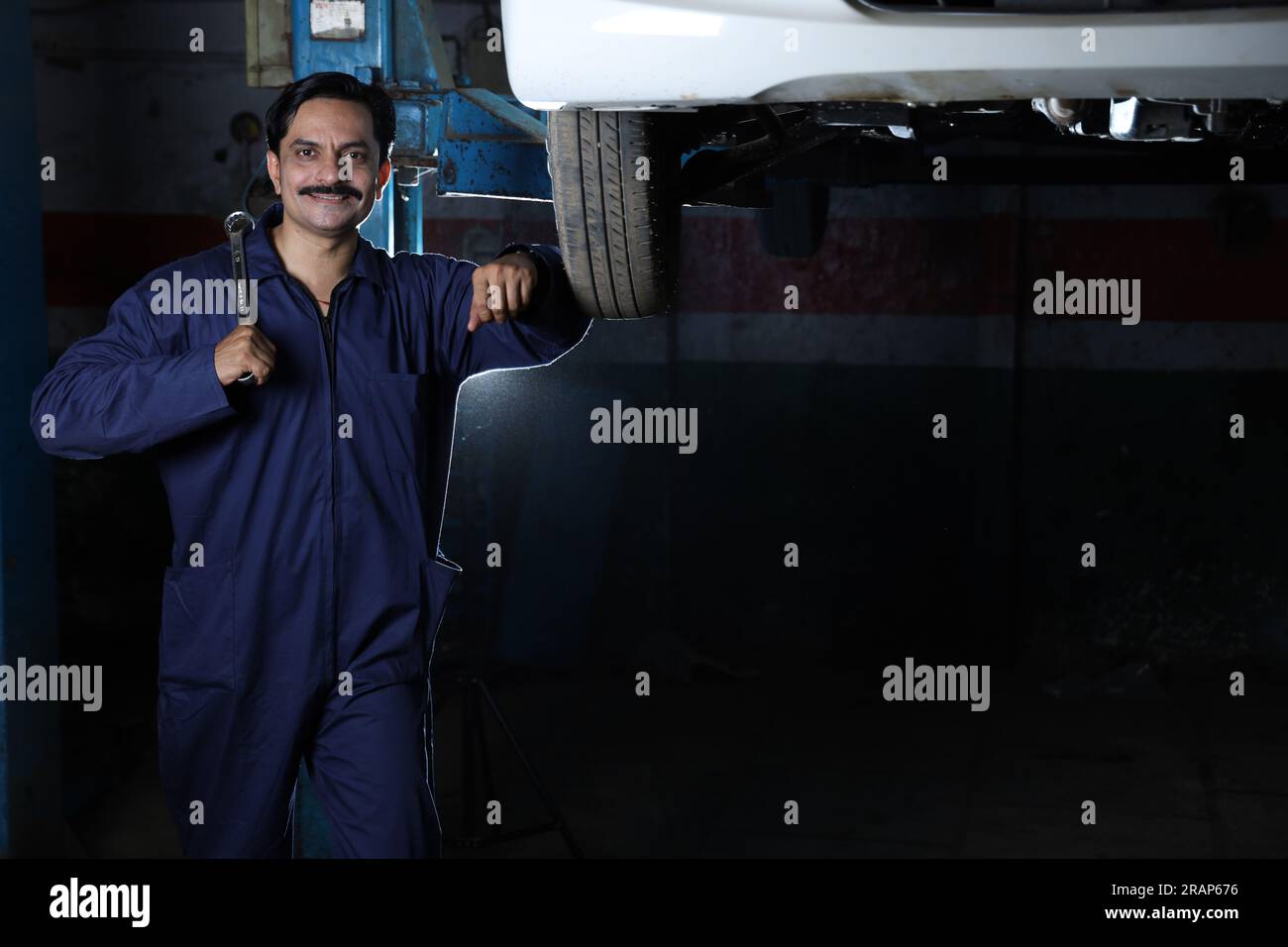 Portrait of a happy car mechanic in moustache standing beside car in ...
