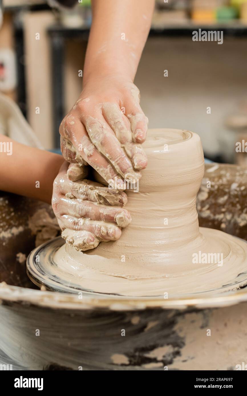 Cropped view of young female ceramicist molding wet clay on spinning ...