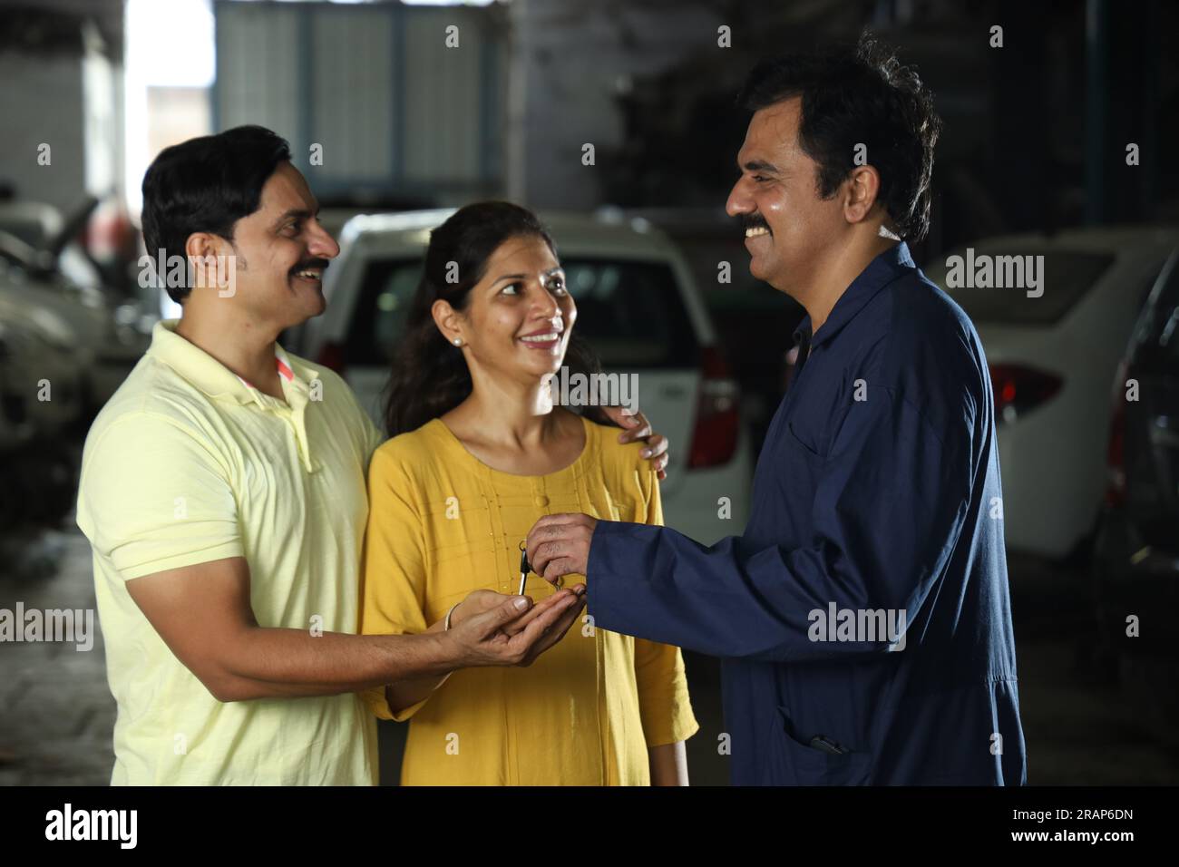 Indian car mechanic delivering the car keys to the happy customers ...