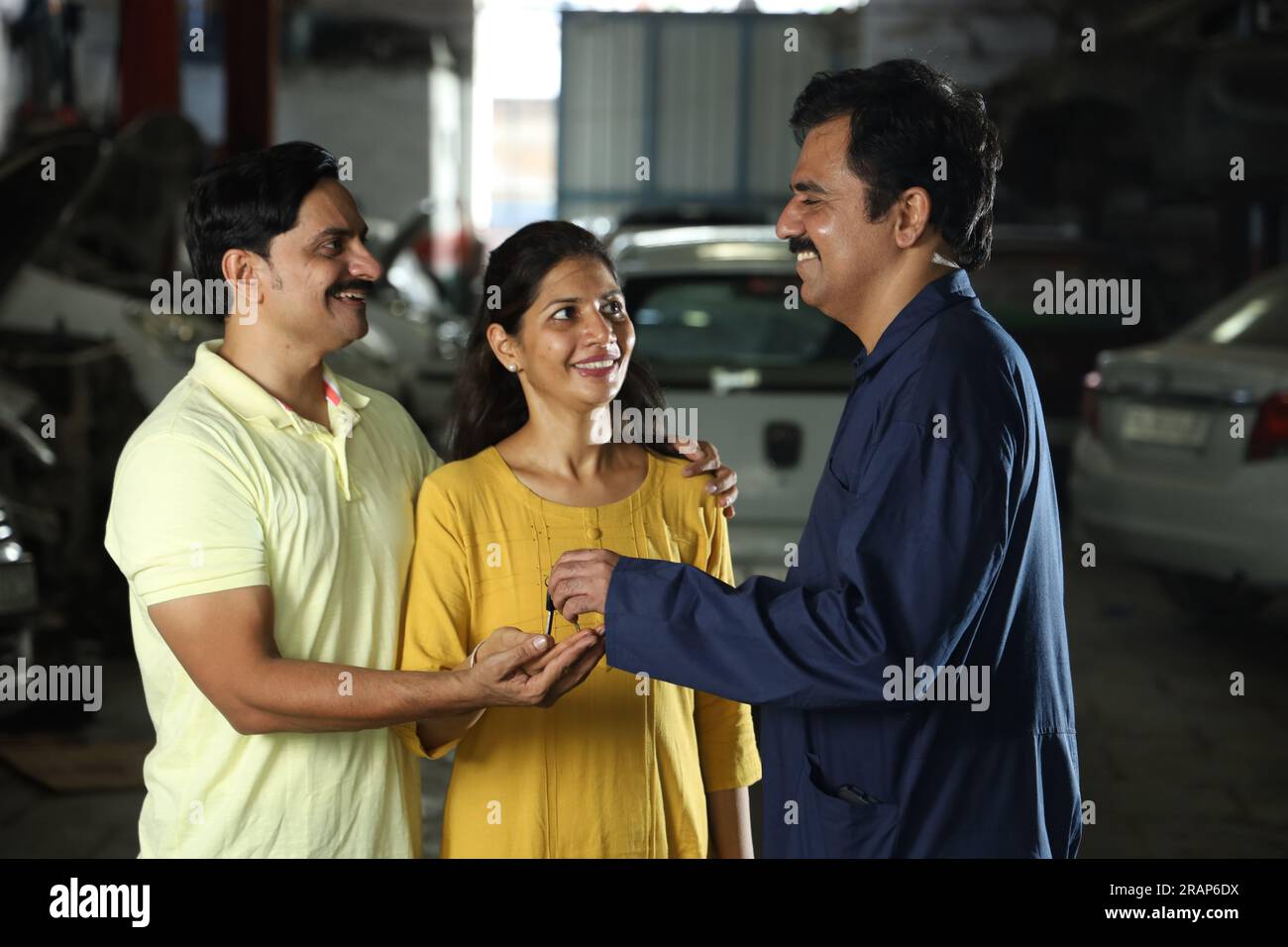 Indian car mechanic delivering the car keys to the happy customers ...